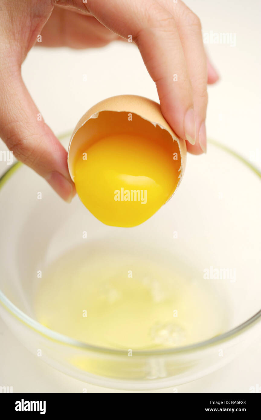 Woman pouring cracked egg into bowl focus on hands Stock Photo - Alamy