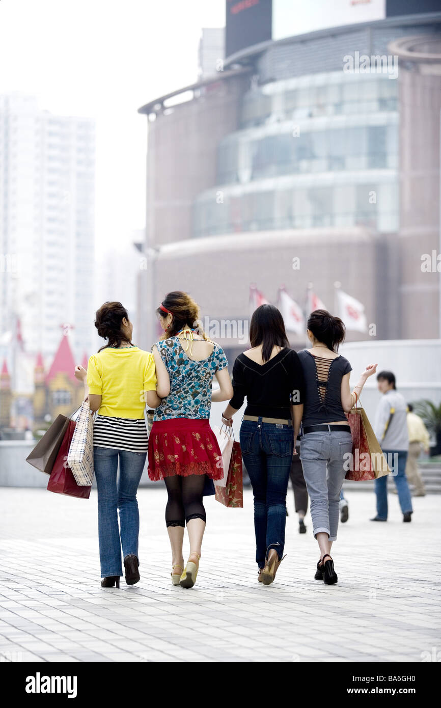 Four young women walking on city street rear view Stock Photo - Alamy