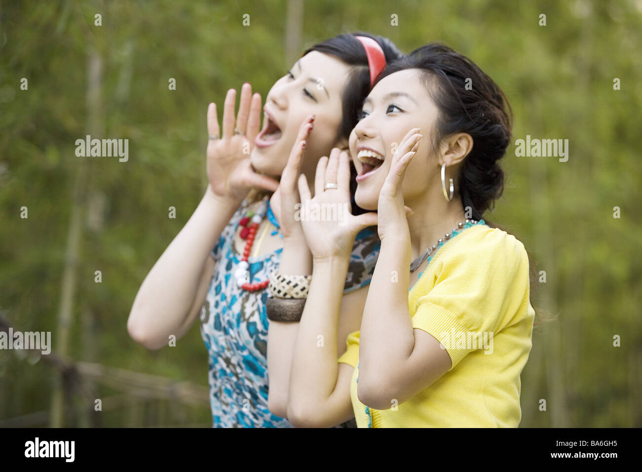 Two young women shouting outdoors smiling portrait Stock Photo - Alamy
