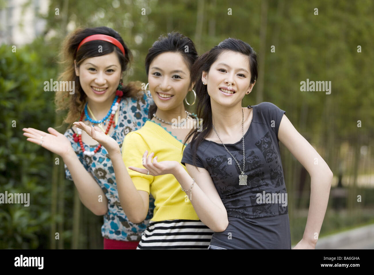Three young women making the same gesturing outdoors smiling portrait ...