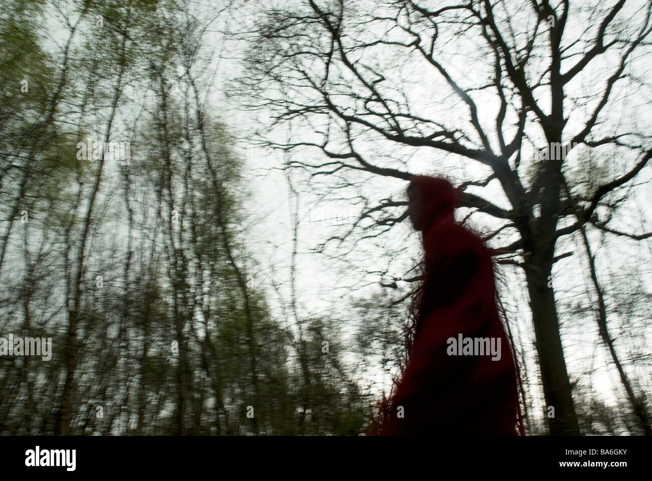 Hooded person walking through overgrown woods Stock Photo - Alamy