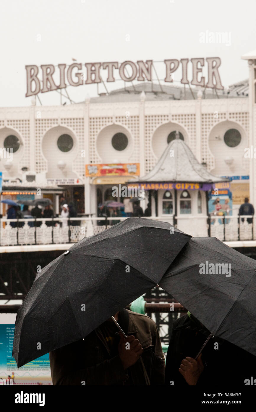 Two people in heavy rain sheltering under black umbrellas, Palace Pier ...