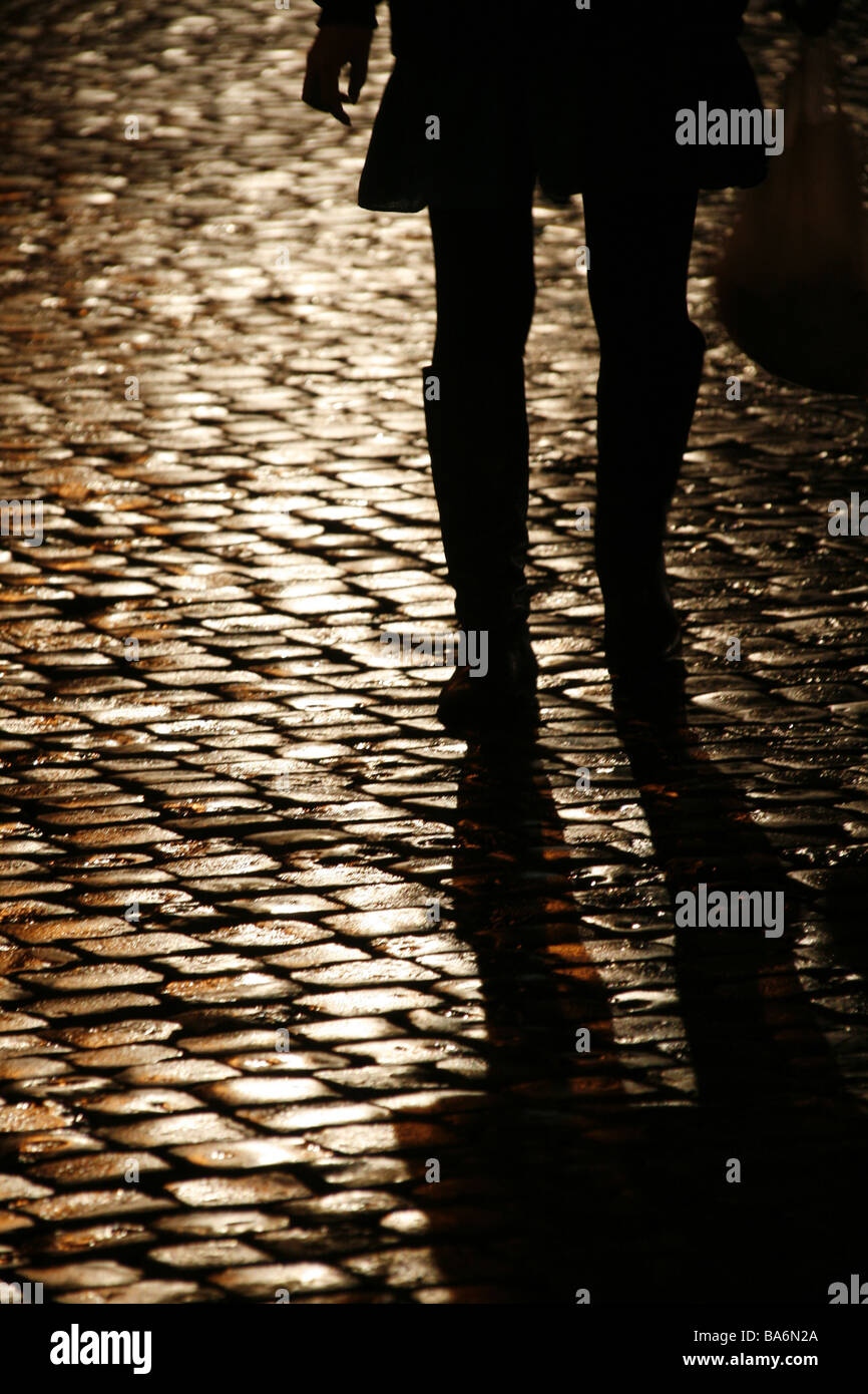 person walking on wet cobbled street at night Stock Photo - Alamy