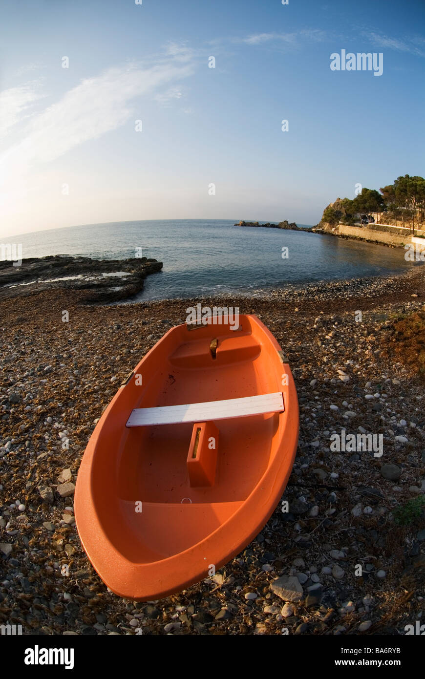 small rowing boat sits on beach in small bay on the spanish ...