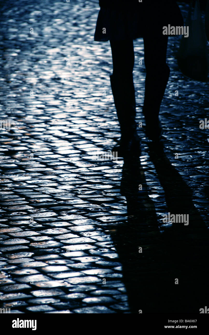 person walking on wet cobbled street at night Stock Photo - Alamy
