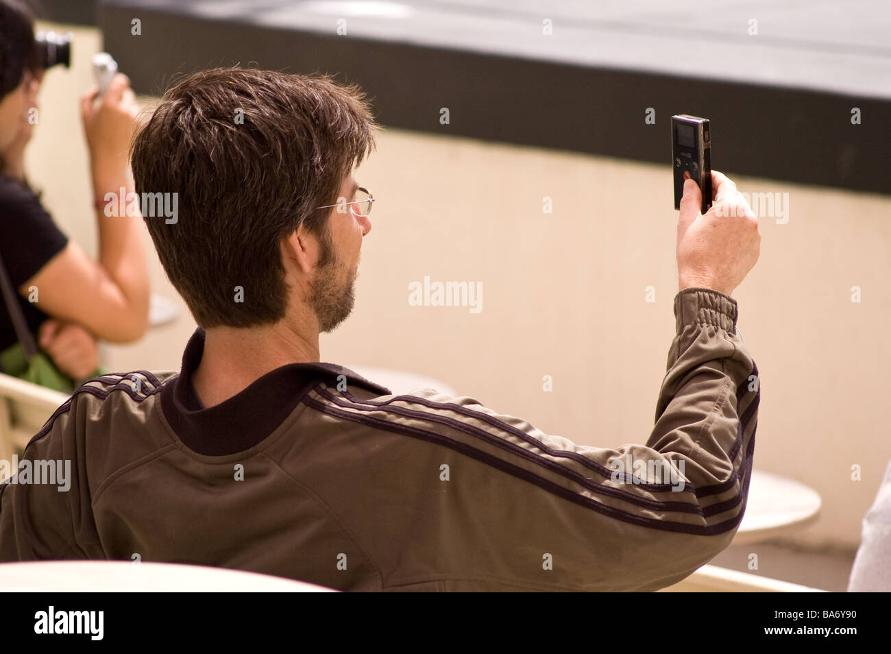 A man filming a music group on stage using a miniature video camera ...