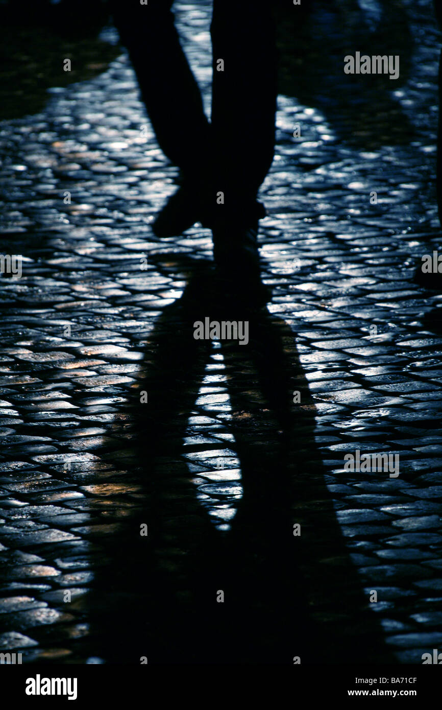 person walking on wet cobbled street at night Stock Photo - Alamy