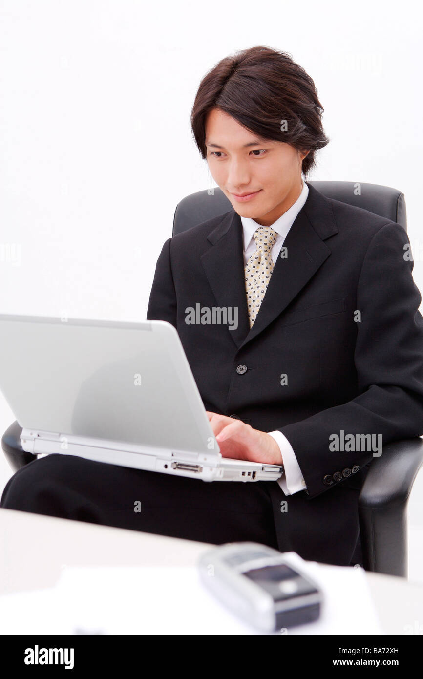 Businessman sitting using laptop smiling Stock Photo - Alamy