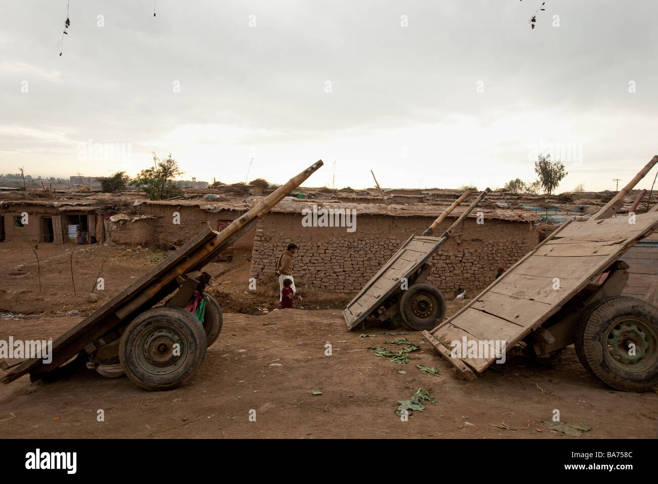 A couple of Afghan residents wander past carts at a settlement on the ...