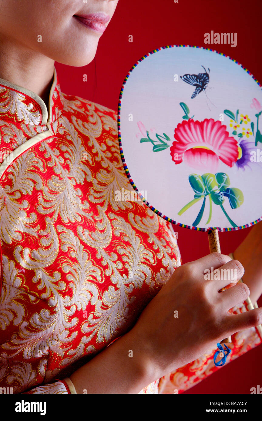 Woman in Cheongsam holding fan side view Stock Photo - Alamy