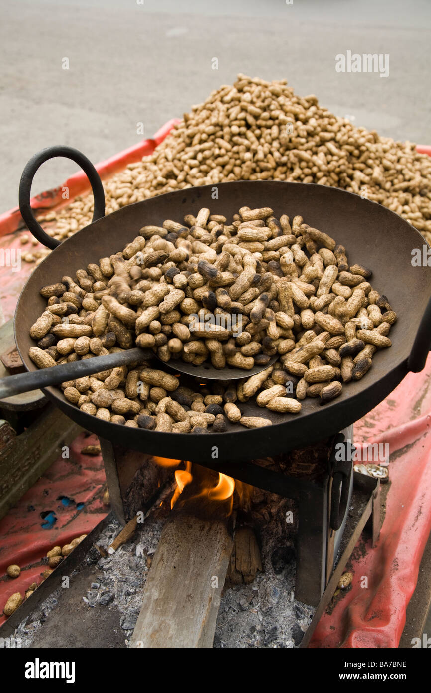 Street vendor's roasting peanuts over an open burner and selling them ...