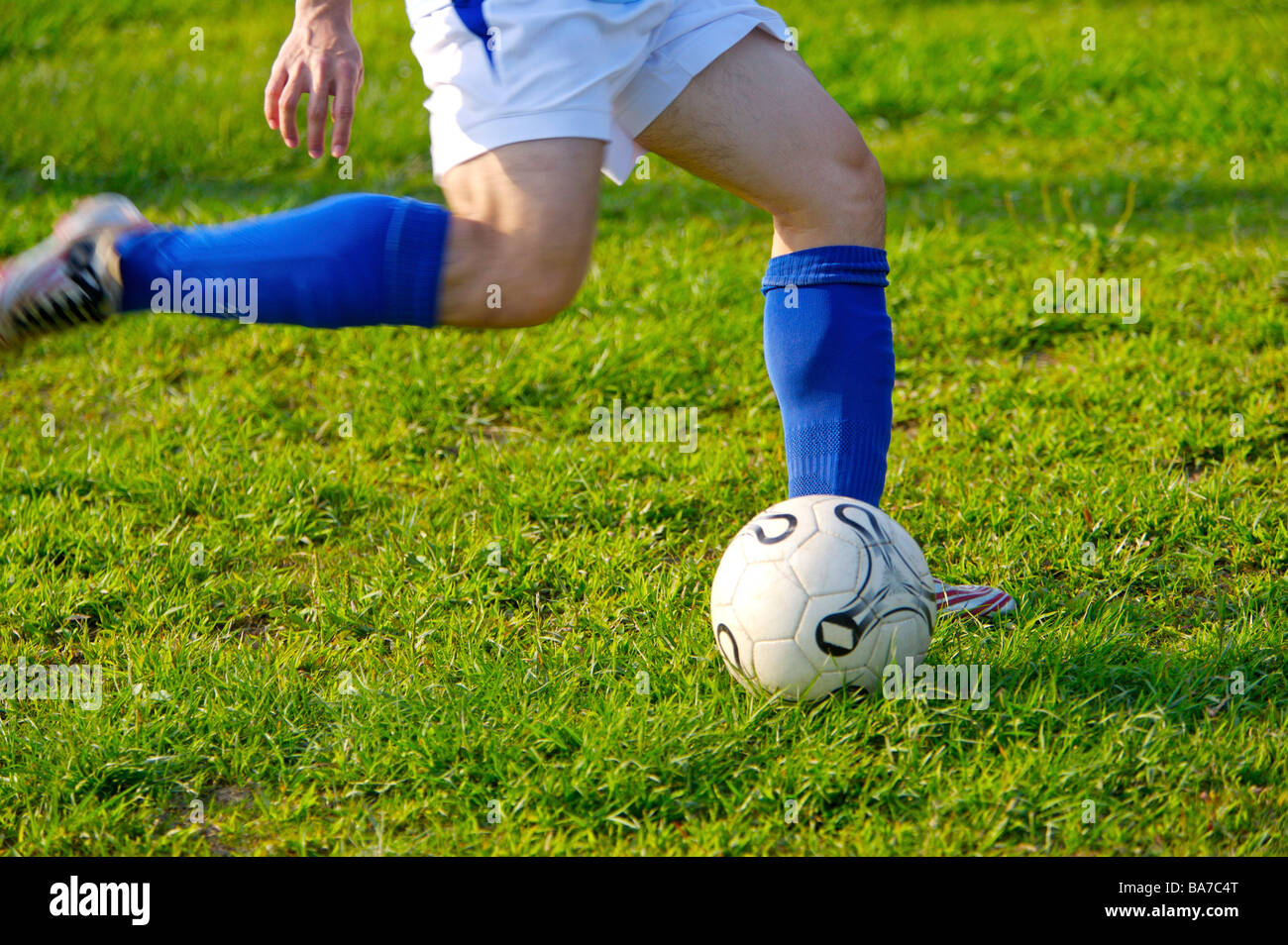 Soccer player kicking ball mid section Stock Photo - Alamy