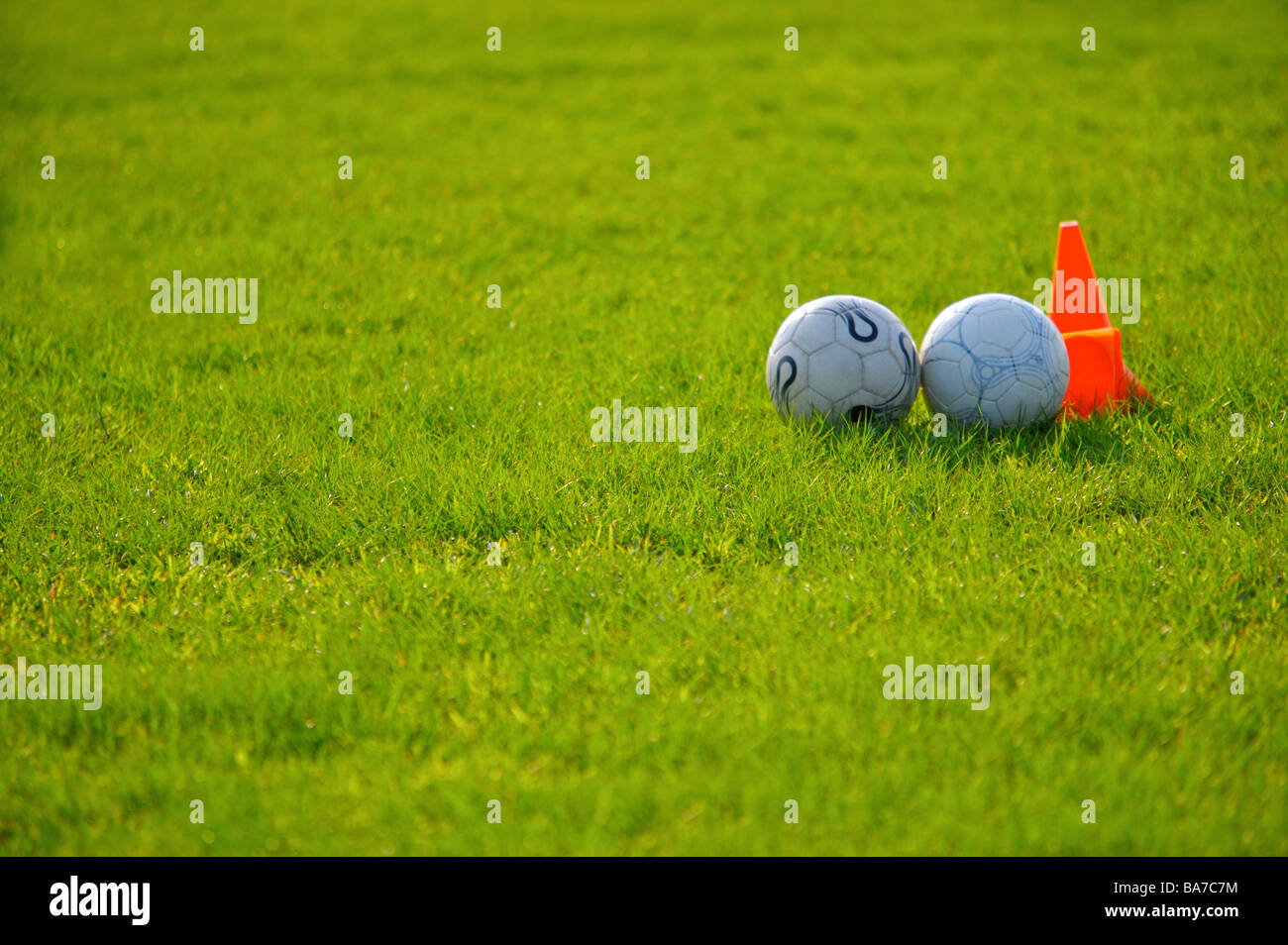 Two soccer balls near red cone Stock Photo - Alamy