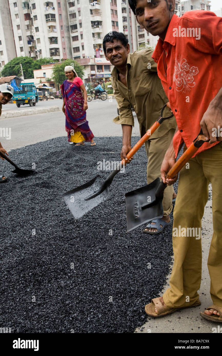Man labourer / road worker spreading asphalt on a road in Surat ...