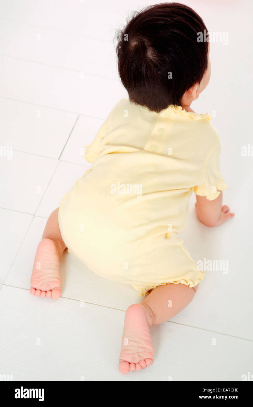 Baby girl crawling on floor rear view Stock Photo - Alamy