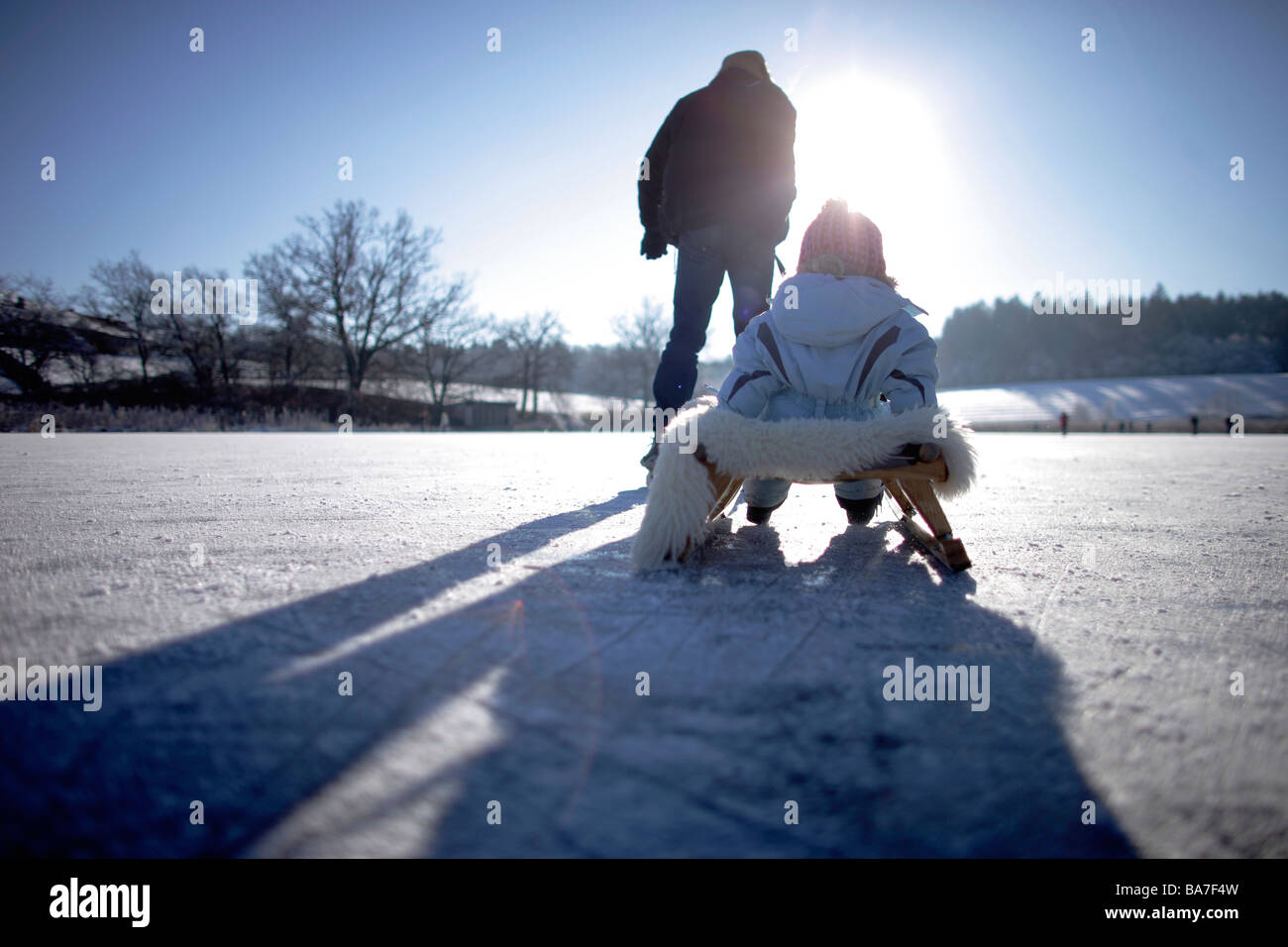 Father pulling sledge with child on frozen lake Buchsee, Munsing ...