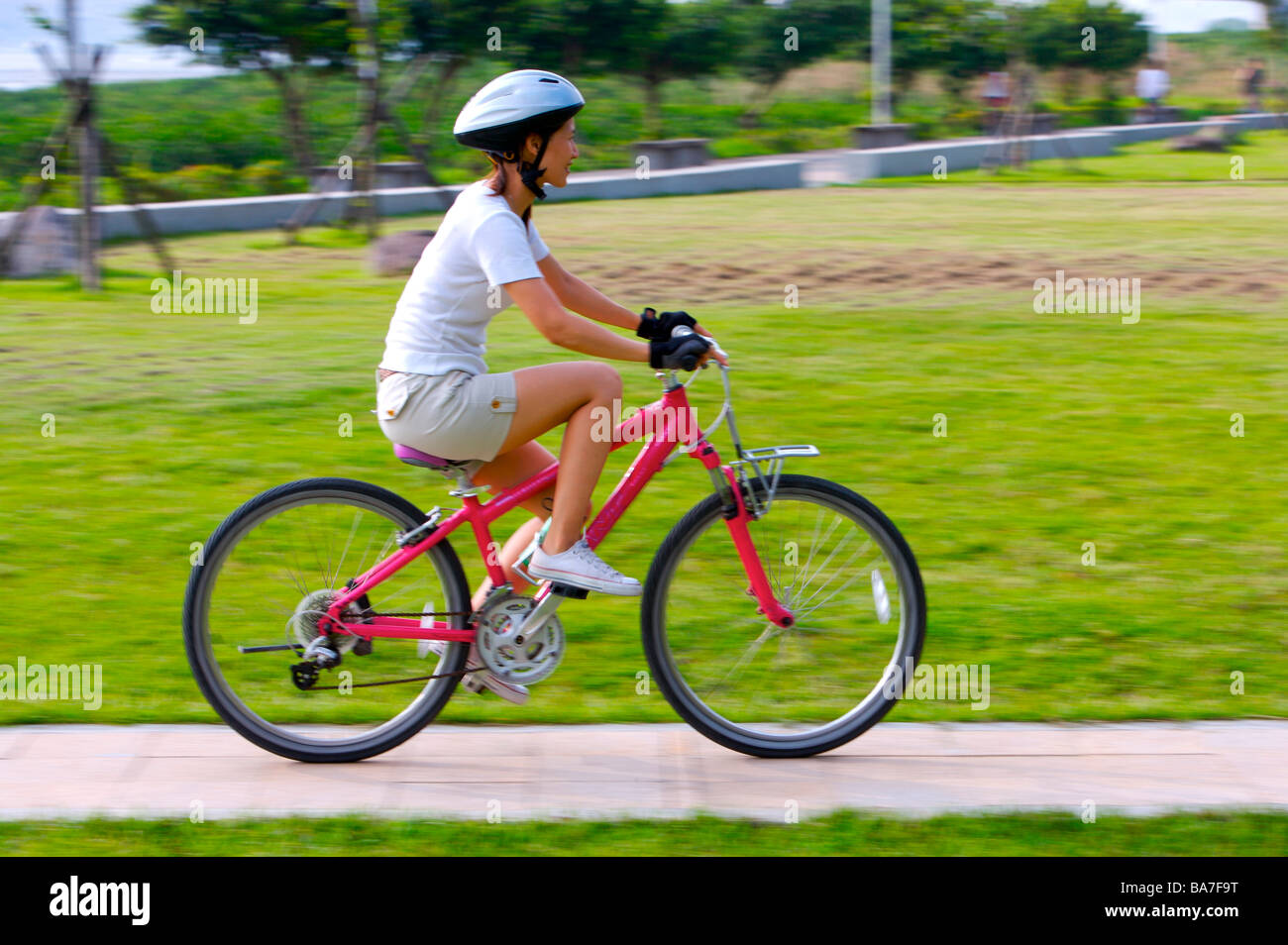 Young woman riding bicycle side view blurred motion Stock Photo - Alamy