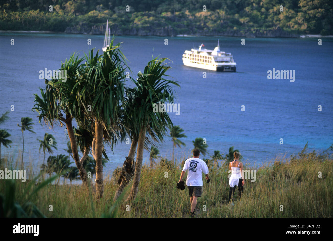 A couple walking along the coast, Blue Lagoon with MV Reef Escape off ...
