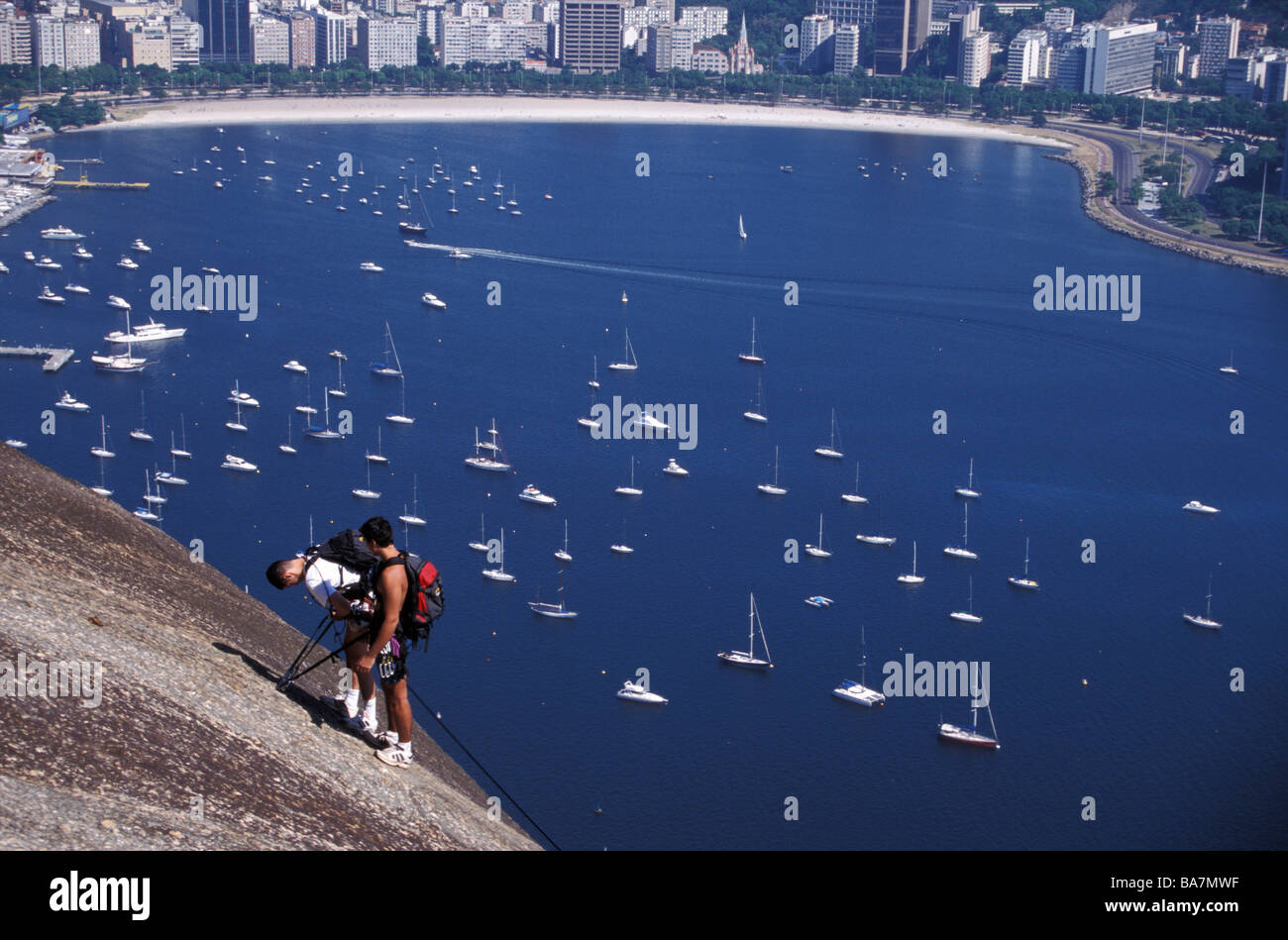 Two young men climbing on Sugarloaf Mountain Pao de Acucar, Rio de ...