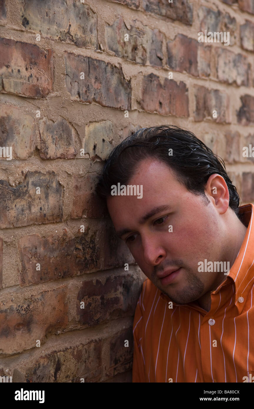 Devastated man leaning his head against a wall Stock Photo - Alamy