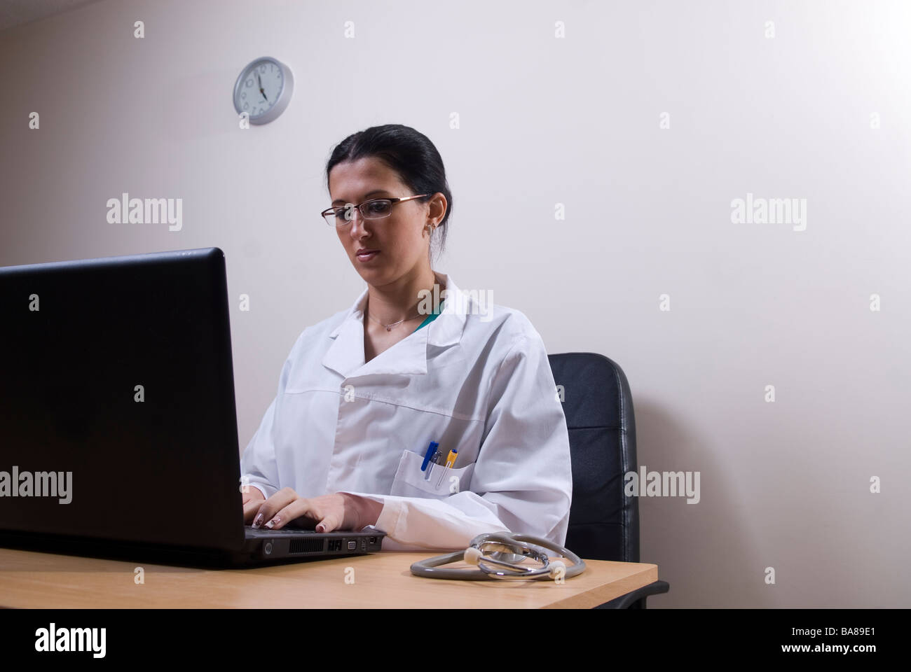 Doctor typing a report on laptop computer inside office Stock Photo - Alamy