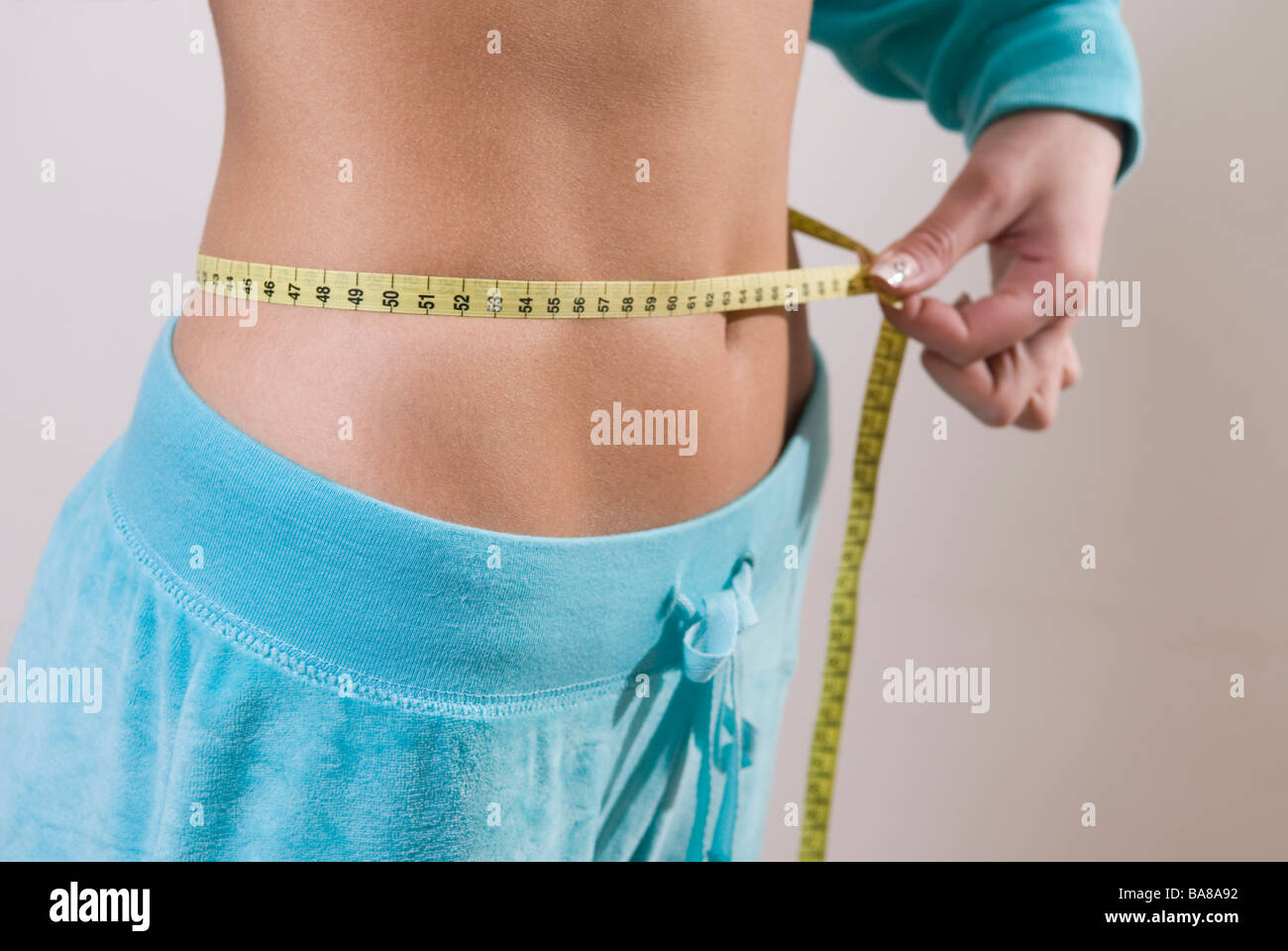 Young woman measuring waist with tape measure Stock Photo - Alamy