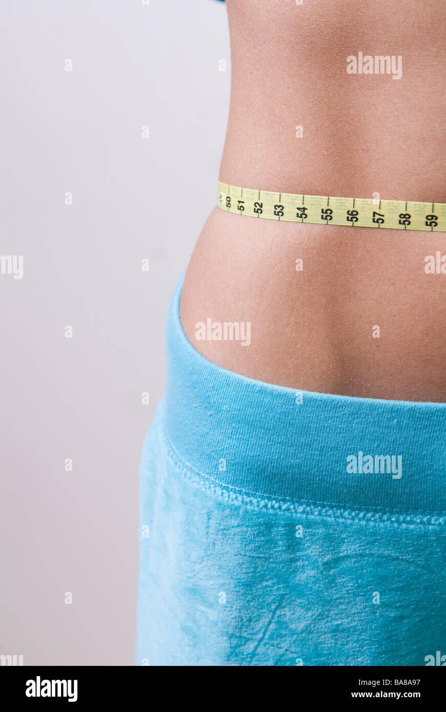Young woman measuring waist with tape measure Stock Photo - Alamy