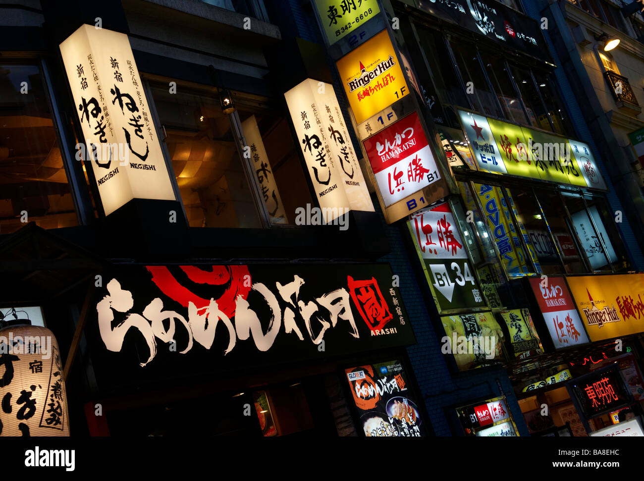 Restaurant and bar signs are illuminated as dusk falls in the Shinjuku ...
