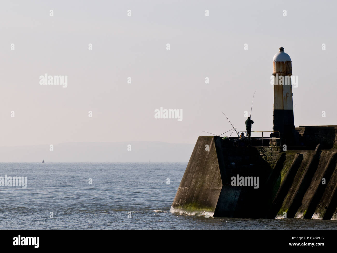 Anglers fishing from the lighthouse jetty in Porthcawl in Wales. Photo ...