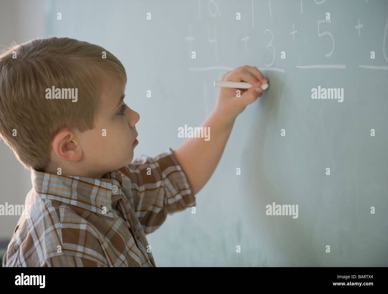 Boy doing math on blackboard Stock Photo - Alamy