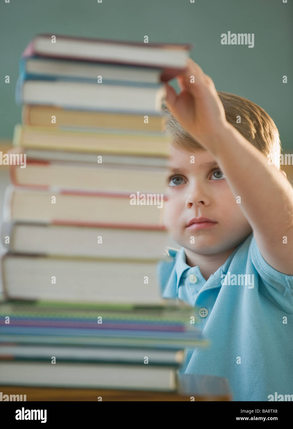 Boy taking book from stack Stock Photo - Alamy