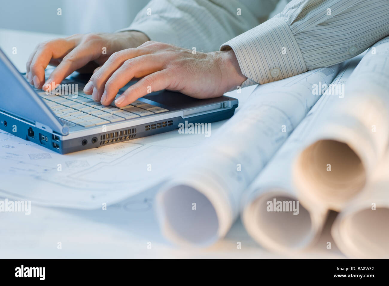 Architect with blueprints and laptop Stock Photo - Alamy