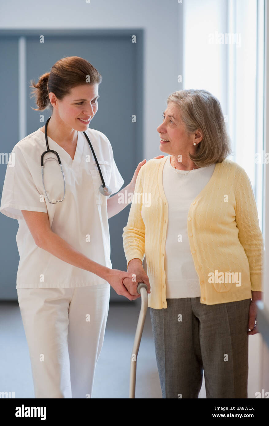Nurse helping senior woman with cane Stock Photo - Alamy