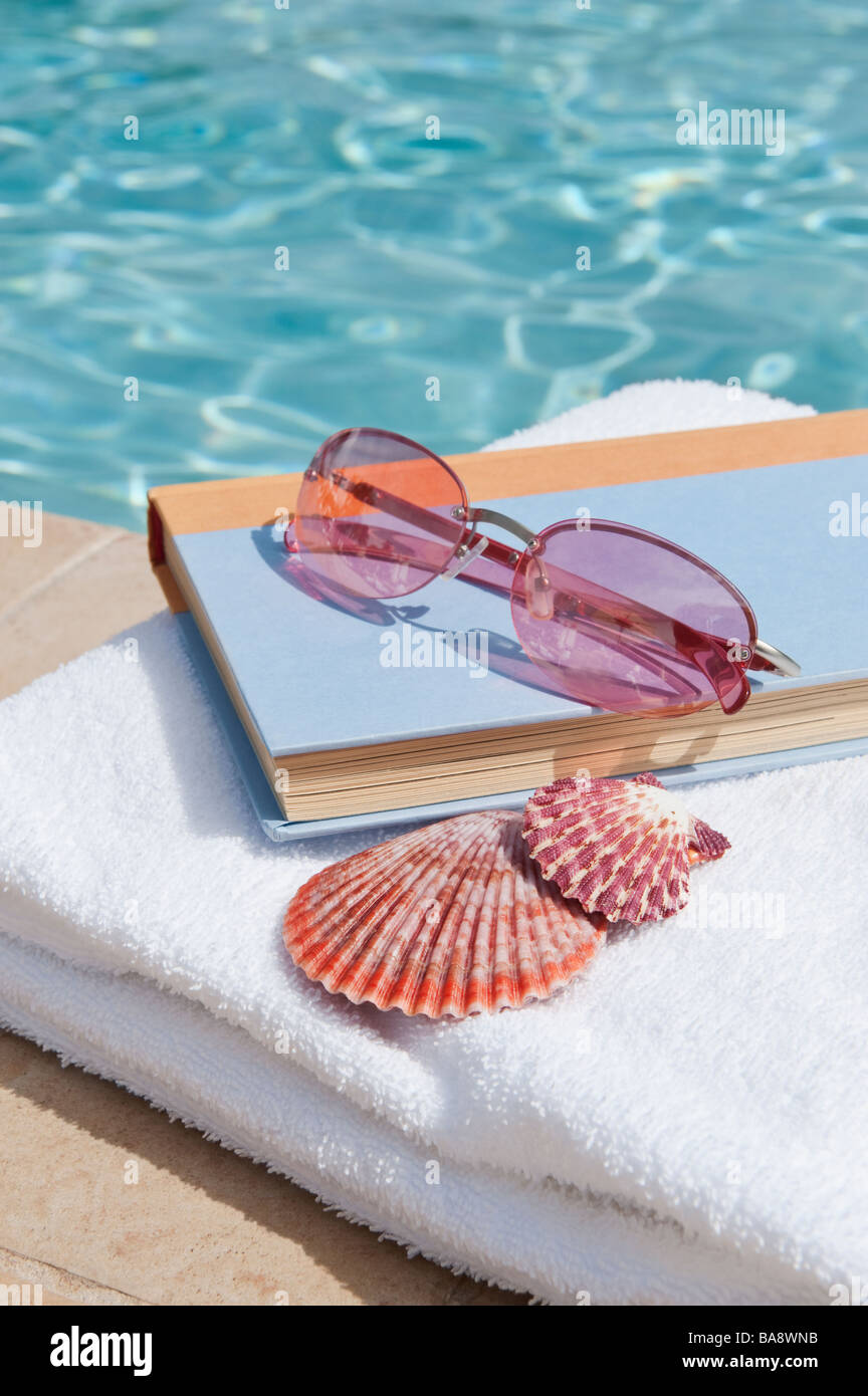 Book and sunglasses by swimming pool Stock Photo - Alamy