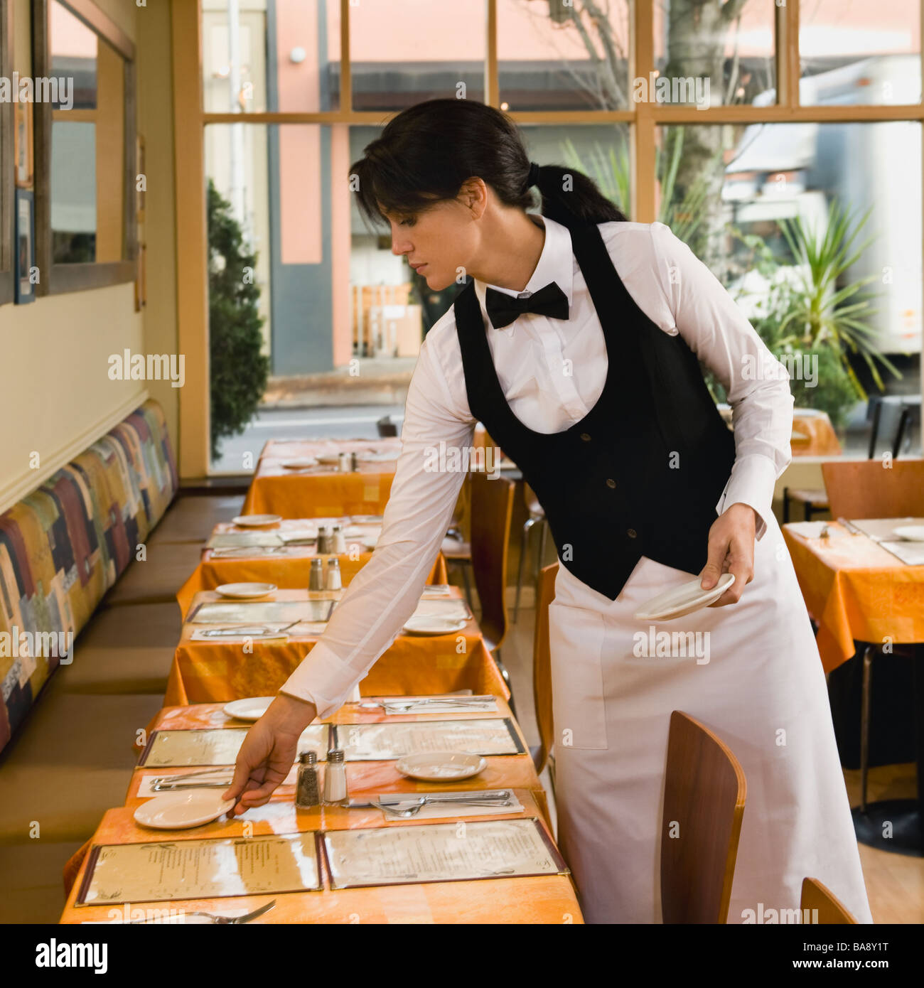 Waitress setting restaurant tables Stock Photo - Alamy