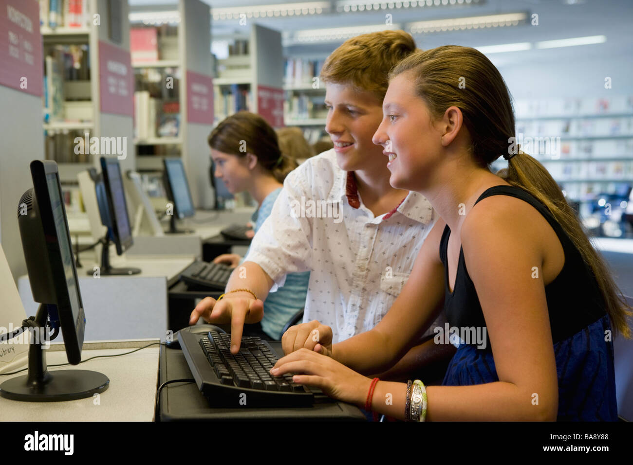 Teenagers using computer in library Stock Photo - Alamy