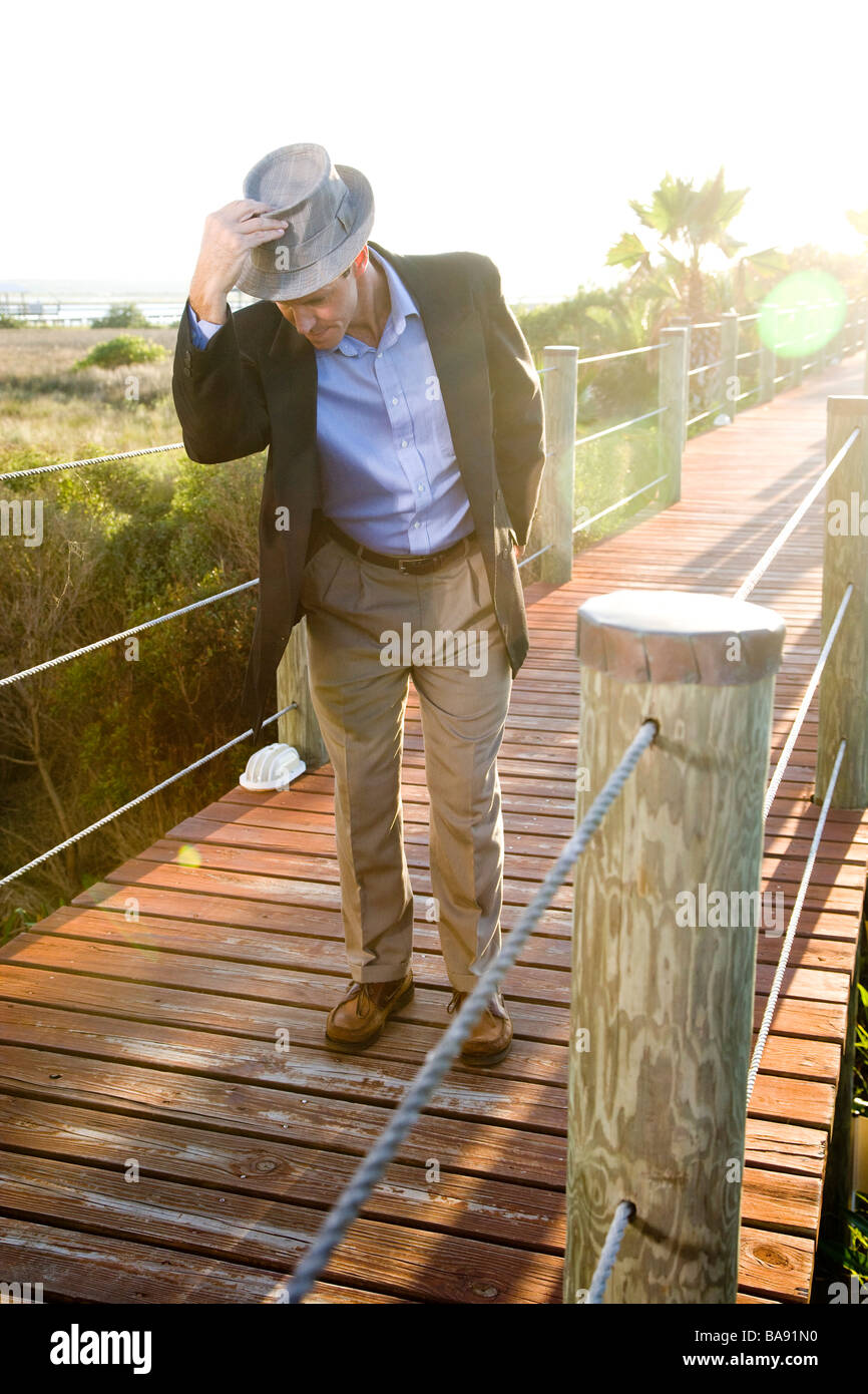 Mid-adult man lifting hat in greeting on boardwalk Stock Photo - Alamy