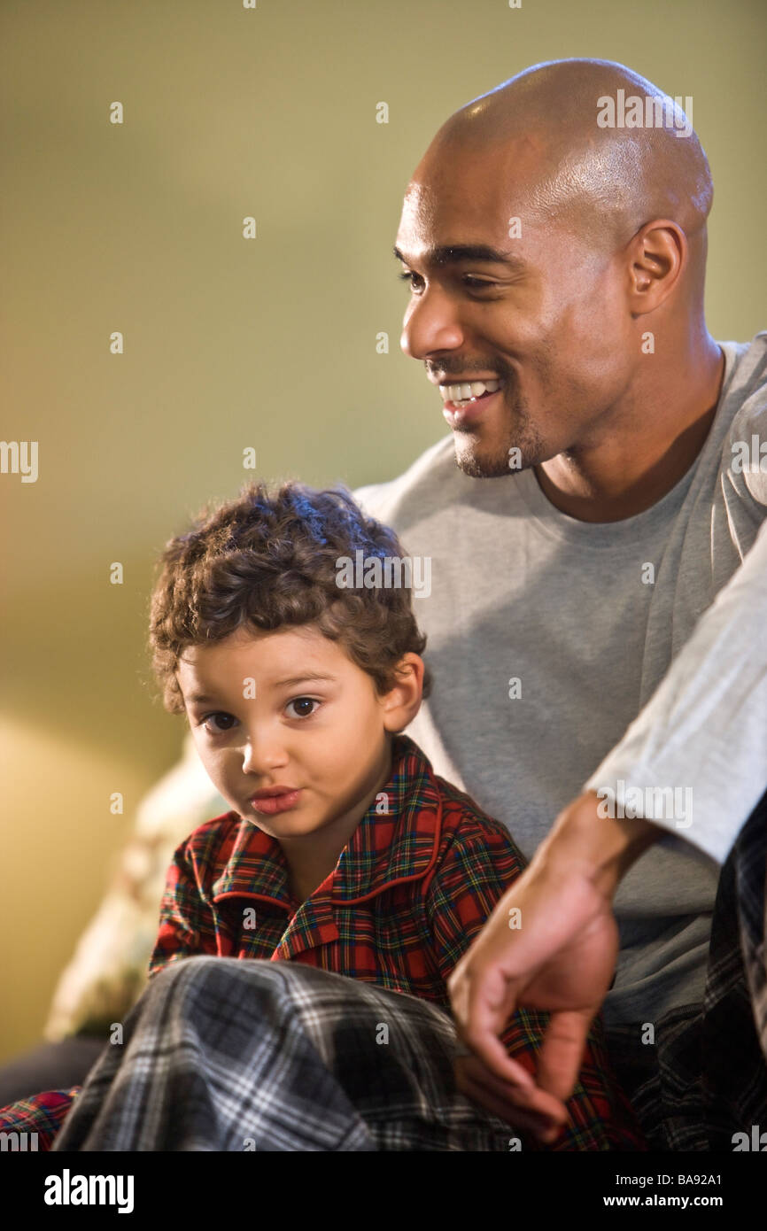 African-American father and son sitting on bed in pajamas Stock Photo ...