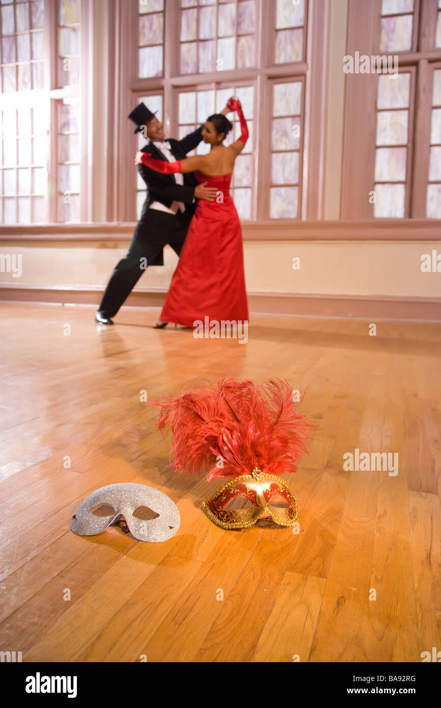 Masks on ballroom floor, couple dancing in background Stock Photo - Alamy