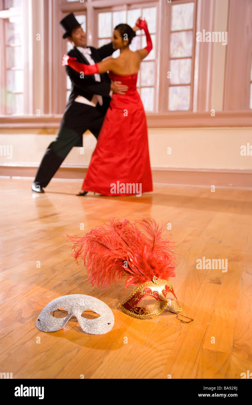 Masks on ballroom floor, couple dancing in background Stock Photo - Alamy