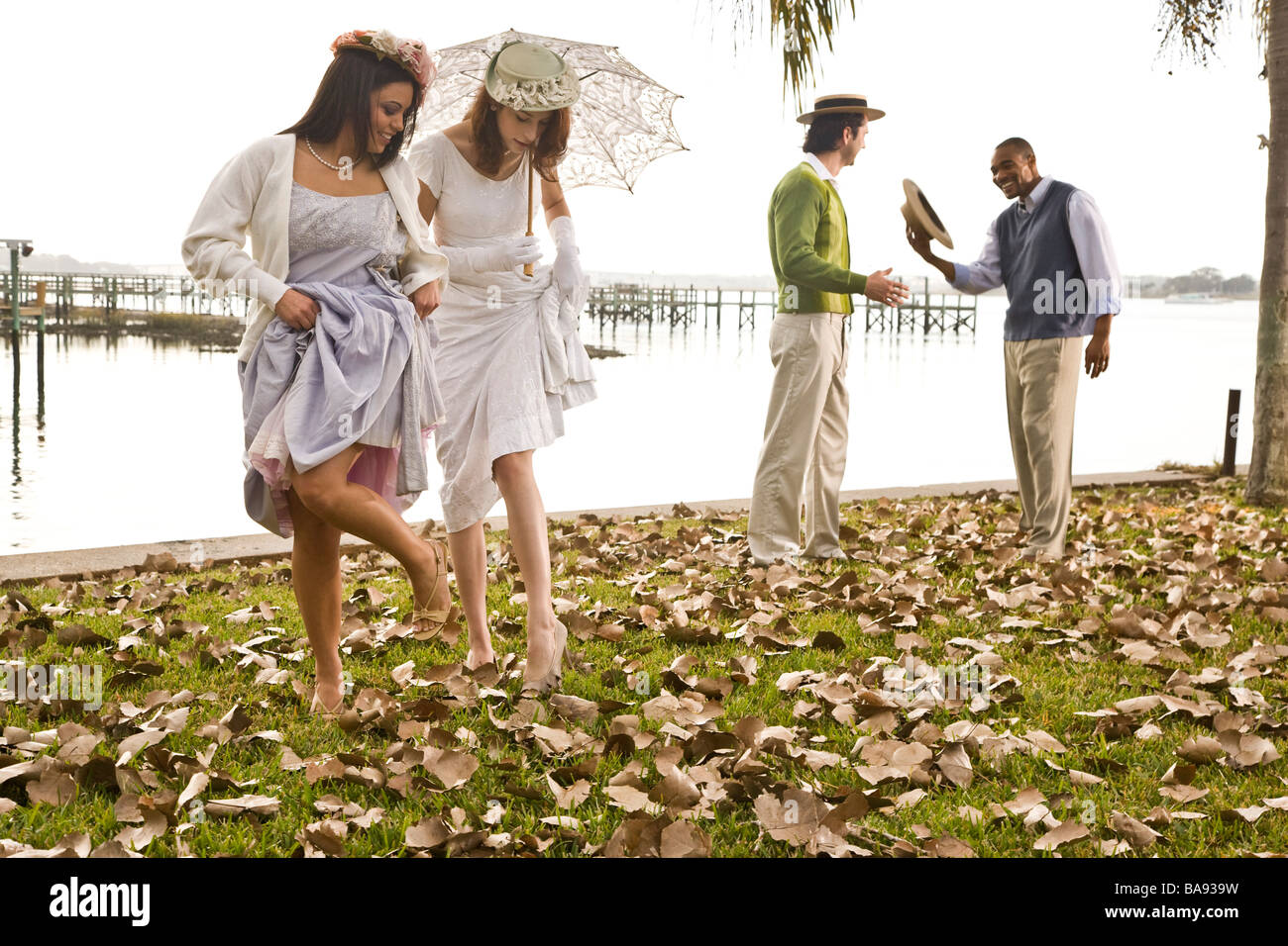 Portrait of 1920s socialites relaxing at garden party on water's edge ...