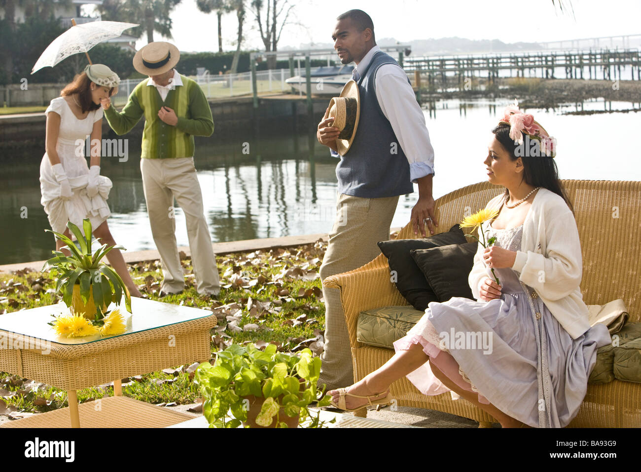 Portrait of 1920s socialites relaxing at garden party on water's edge ...