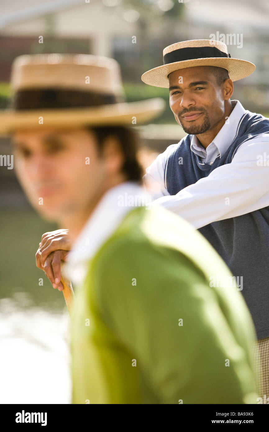 Portrait of 1920s socialite men relaxing at garden party on water's ...