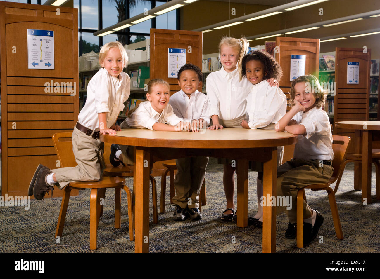 Portrait of elementary school kids sitting at table in library Stock ...