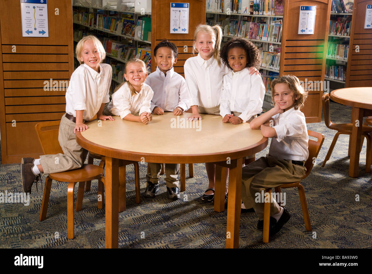Portrait of elementary school kids sitting at table in library Stock ...