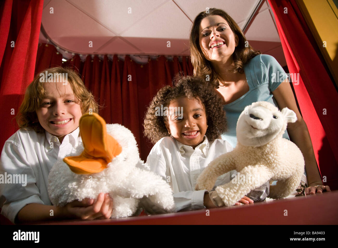 Portrait of elementary school teacher and pupils in puppet theatre ...