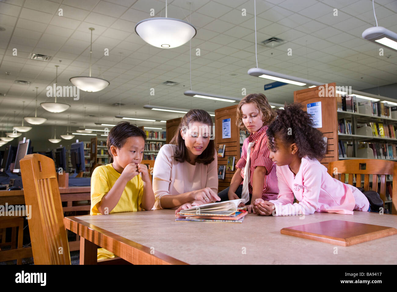 Elementary school teacher teaching pupils in library Stock Photo - Alamy