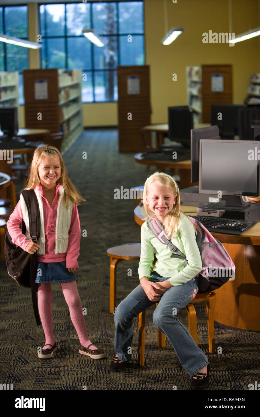 Two elementary school girls smiling in library Stock Photo - Alamy