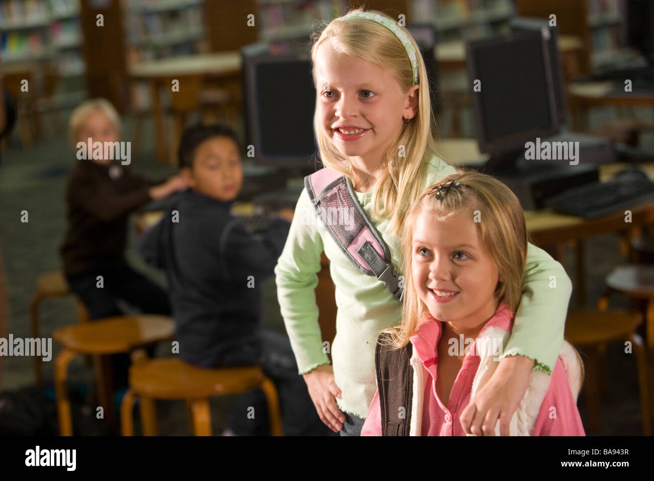 Two elementary school girls smiling in library Stock Photo - Alamy