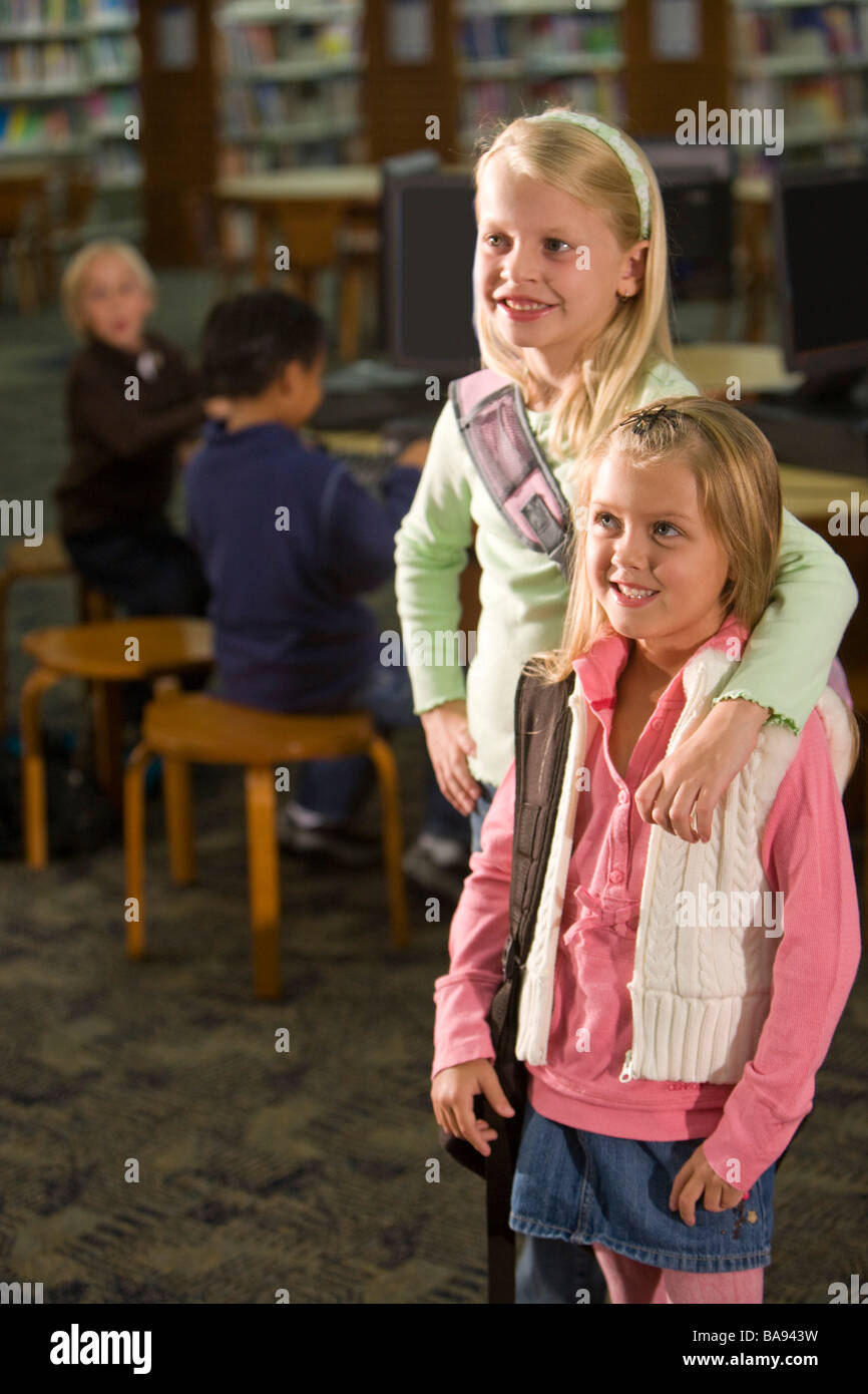 Two elementary school girls smiling in library Stock Photo - Alamy